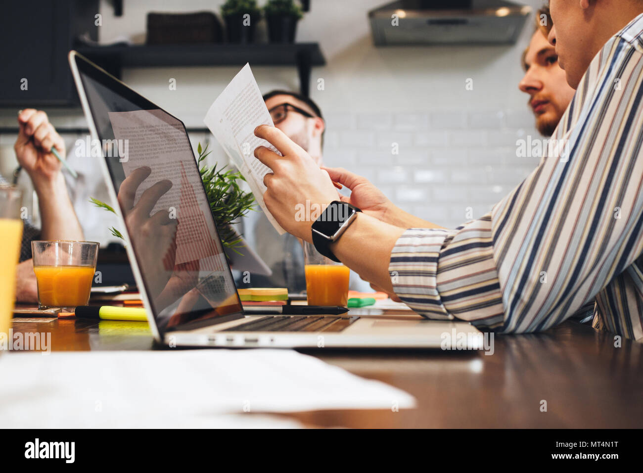 Businessman with a smartwatch on his hand is holding a paper document ...