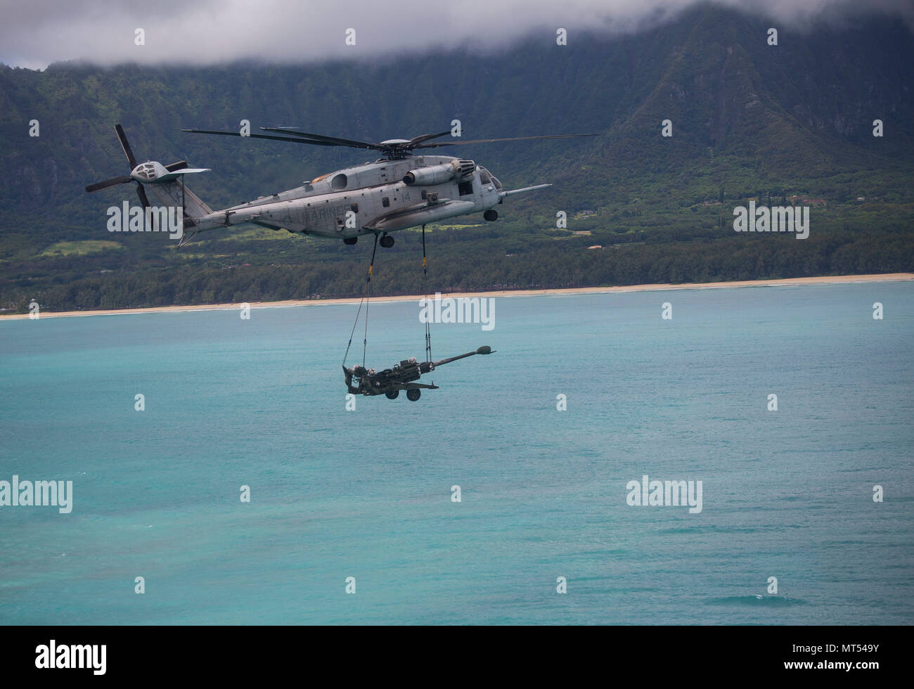 A CH-53E Super Stallion helicopter carries a M777 Howitzer over the ...