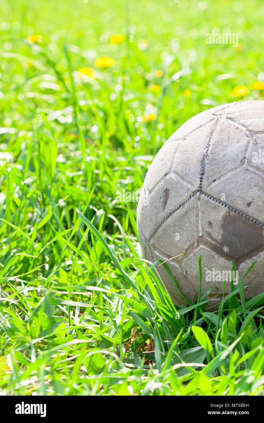 Old soccer ball forgotten in the green grass field. The football ...
