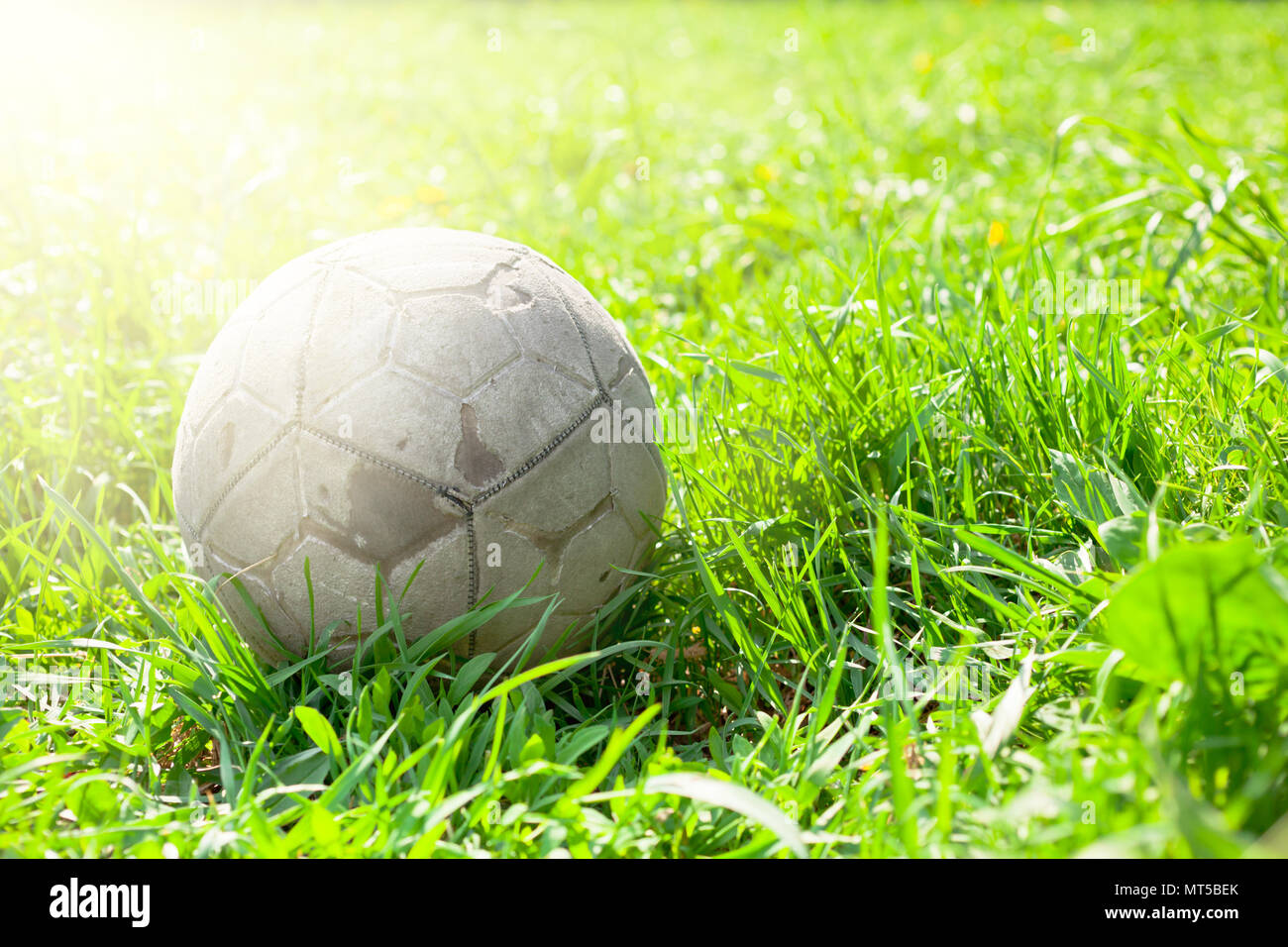 Old soccer ball forgotten in the green grass field. The football ...