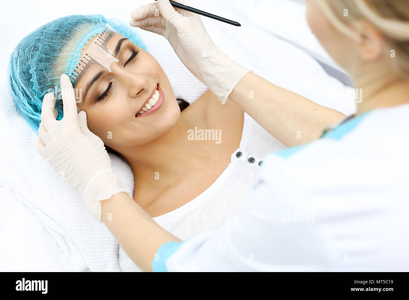 Professional beautician is going to correct eyebrow line at woman face ...