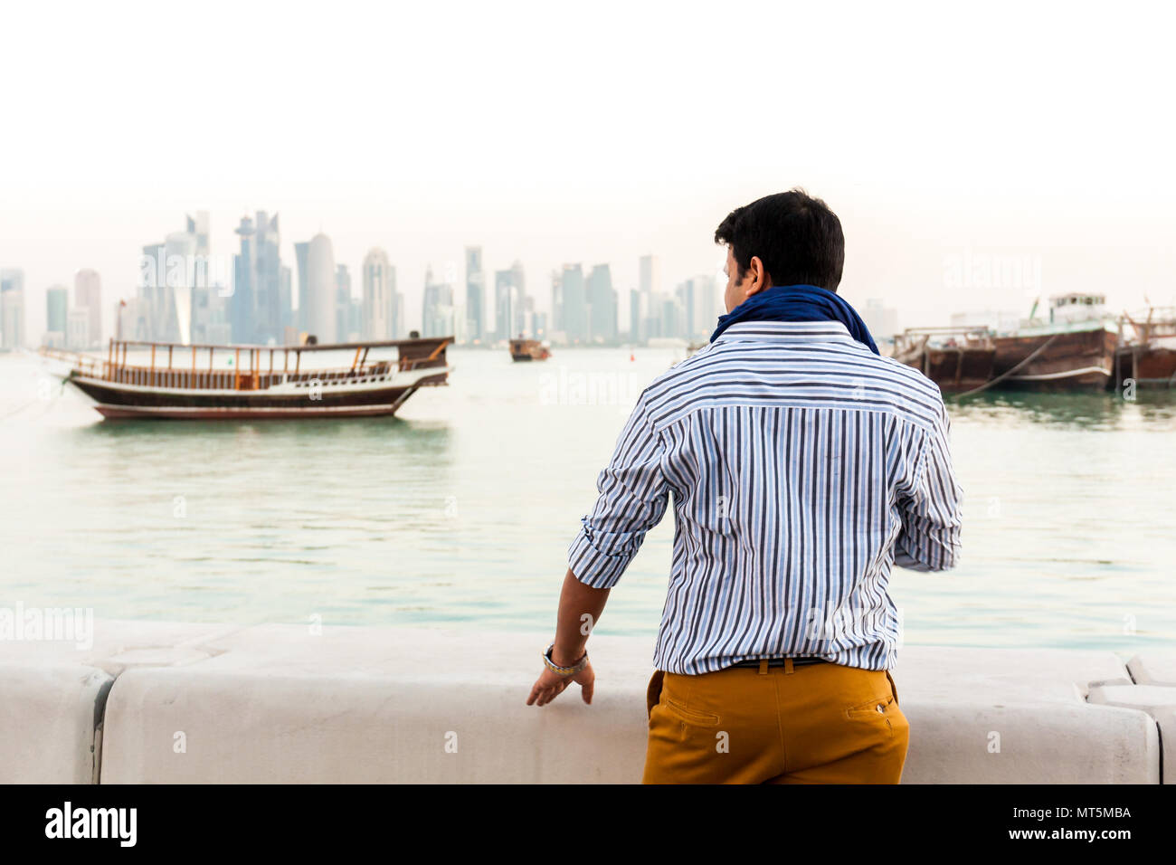 Back view of young Indian man outside looking at the view of cityscape ...