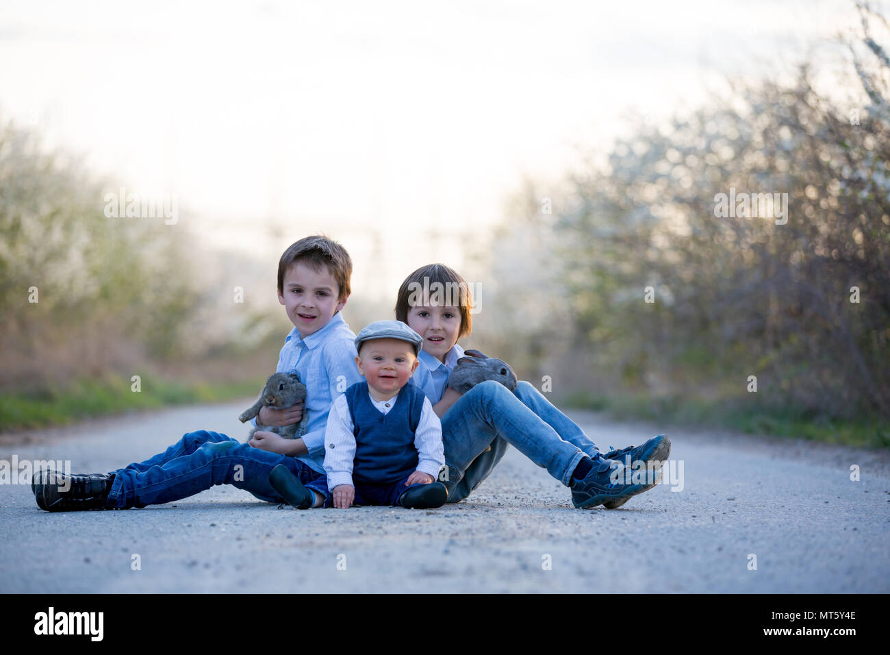 Three children, boy brothers in park, playing with little bunnies on ...