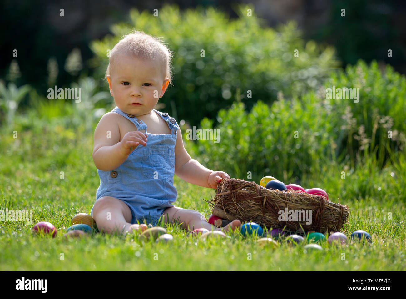 Cute child, playing with little bunny and easter eggs in a blooming ...