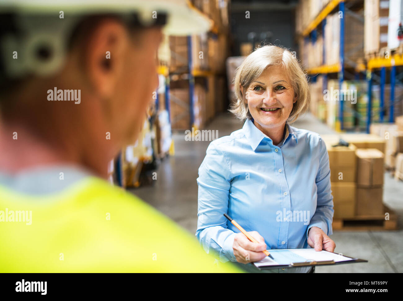 Senior woman manager and man worker working in a warehouse Stock Photo ...
