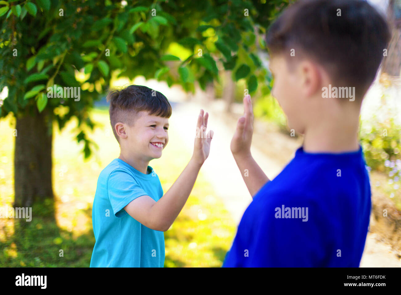 Young caucasian boys high five at park Stock Photo - Alamy