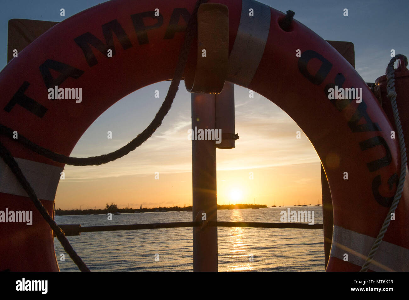 The sunset is seen from the fantail of the Coast Guard Cutter Tampa ...