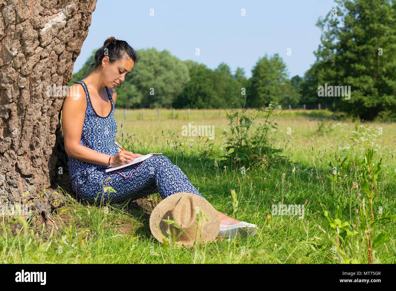Woman sitting against tree trunk hi-res stock photography and images ...