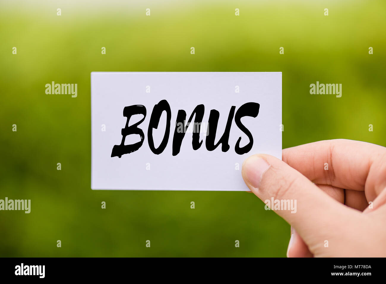 Hand holding Bonus card with green background. Business achievement ...