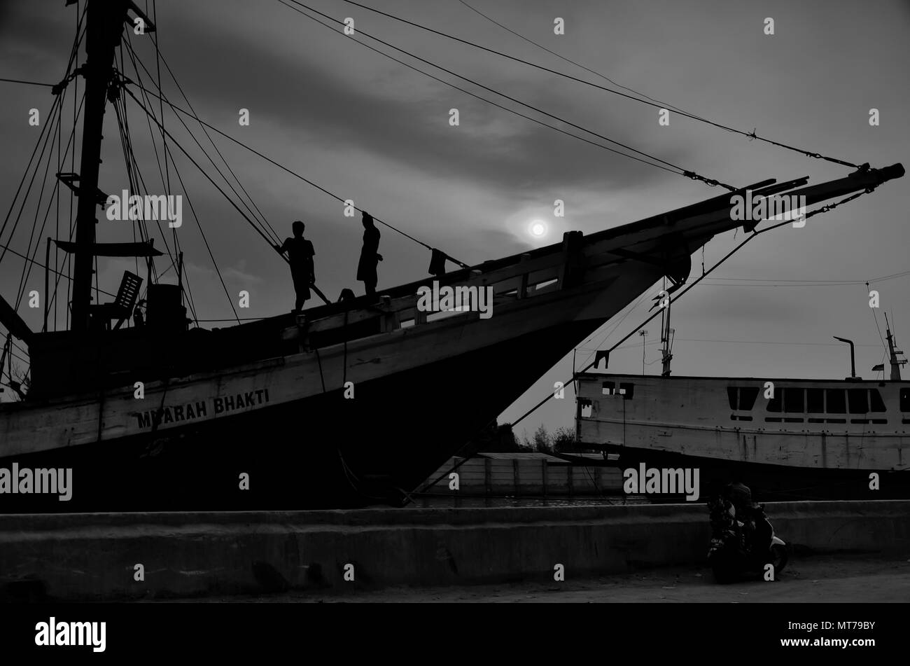 Fisherman and sailor enjoying sunset at a traditional ship boat docking ...