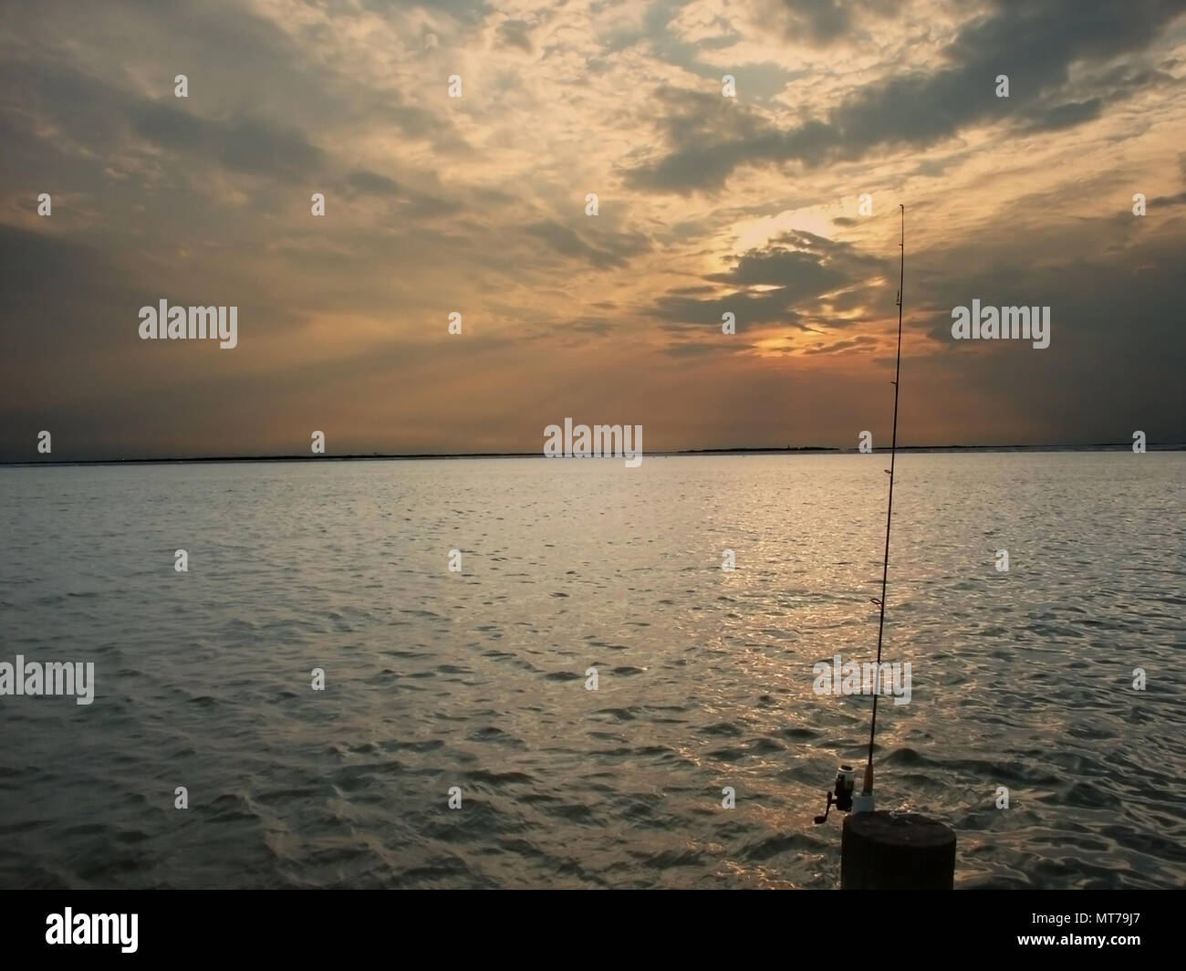Sunset over ocean. Fishing rod Stock Photo - Alamy