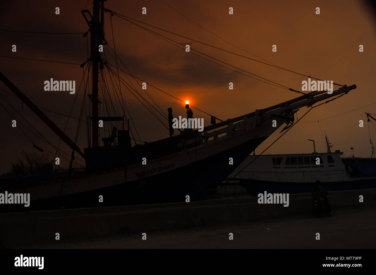 Fisherman and sailor enjoying sunset at a traditional ship boat docking ...