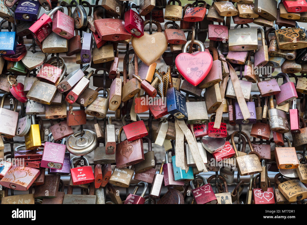 A collection of colorful love locks attached to a fence, with names and ...