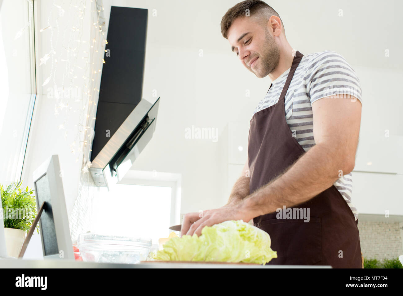 Content handsome man in apron cooking at home Stock Photo - Alamy