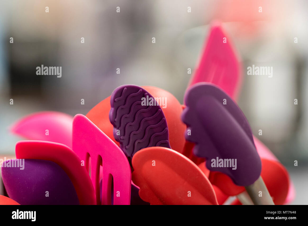 a selection of brightly coloured plastic kitchen implements in a pot on ...