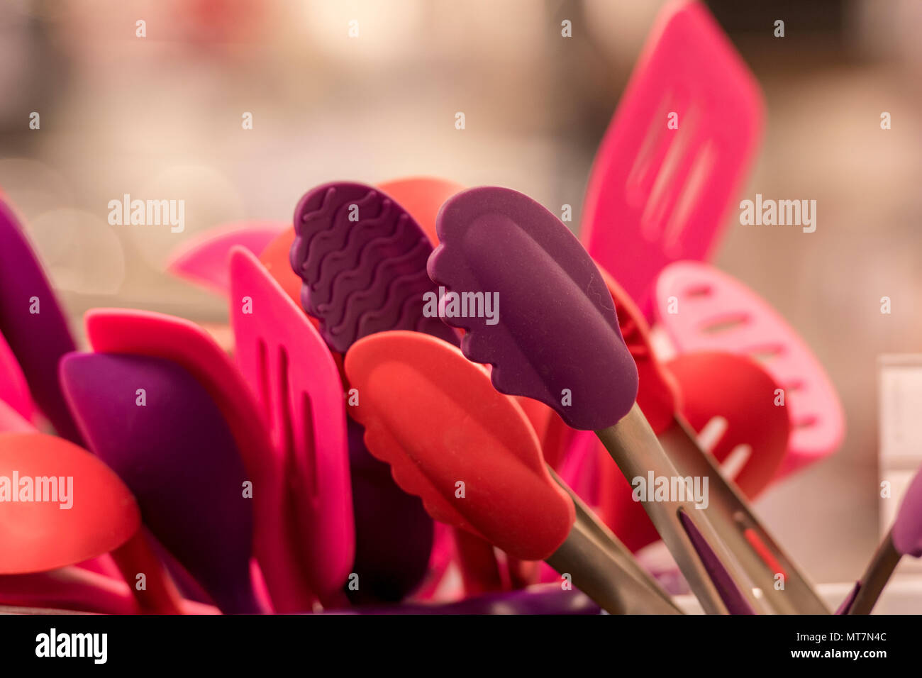 a selection of brightly coloured plastic kitchen implements in a pot on ...