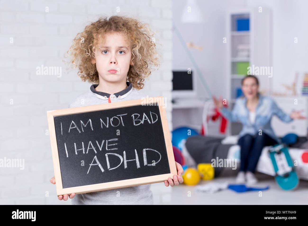 Sad ADHD boy holding small board, shouting mother in background Stock ...