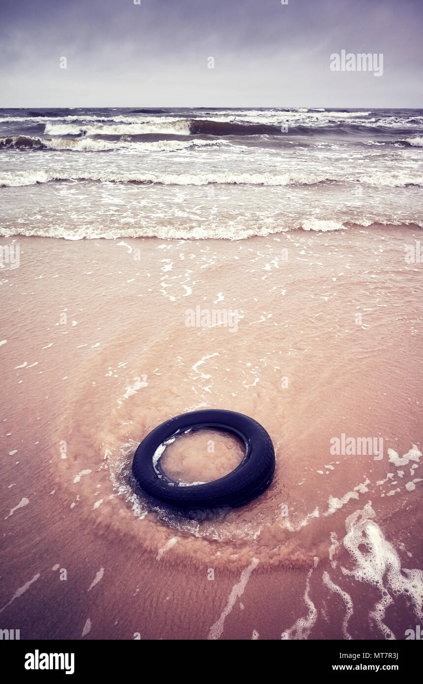 Old black rubber tire left on a beach, environment pollution concept ...