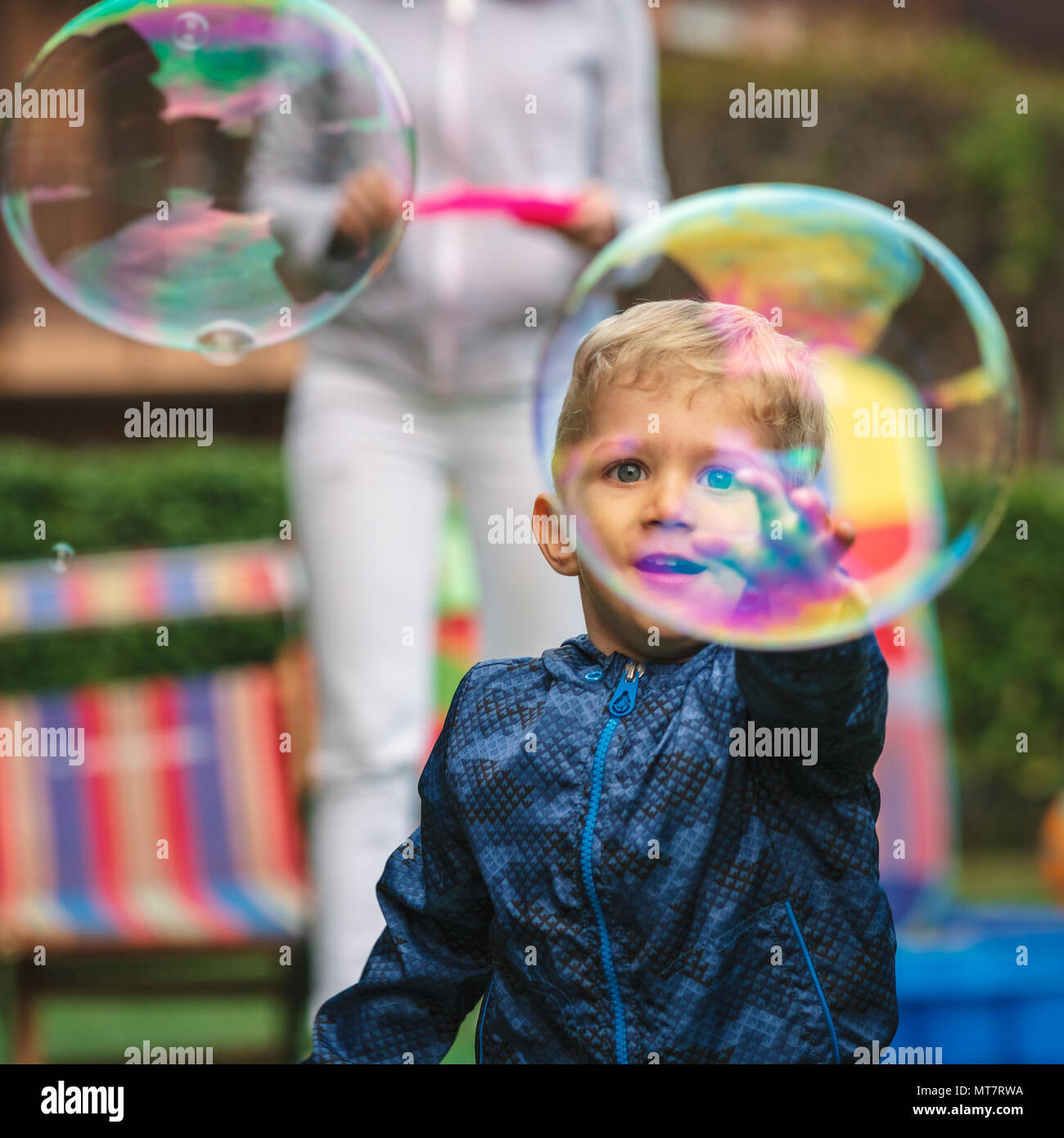 Beautiful baby boy enjoying blowing big soap bubbles in the autumn ...