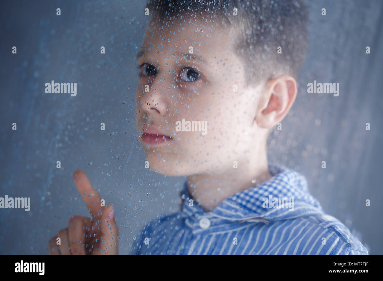Sad boy behind the window on a rainy day Stock Photo - Alamy