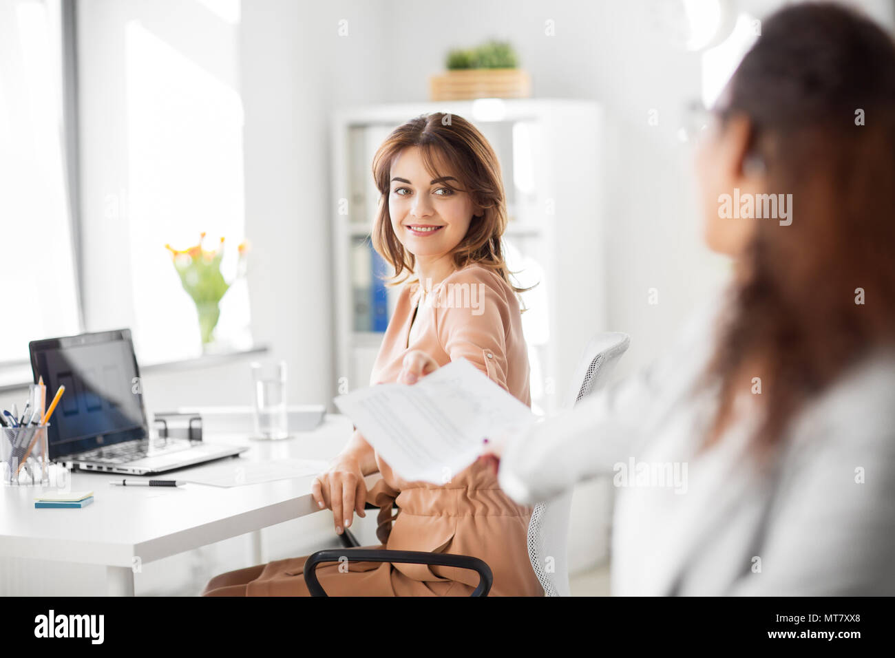 businesswomen giving each other papers at office Stock Photo - Alamy