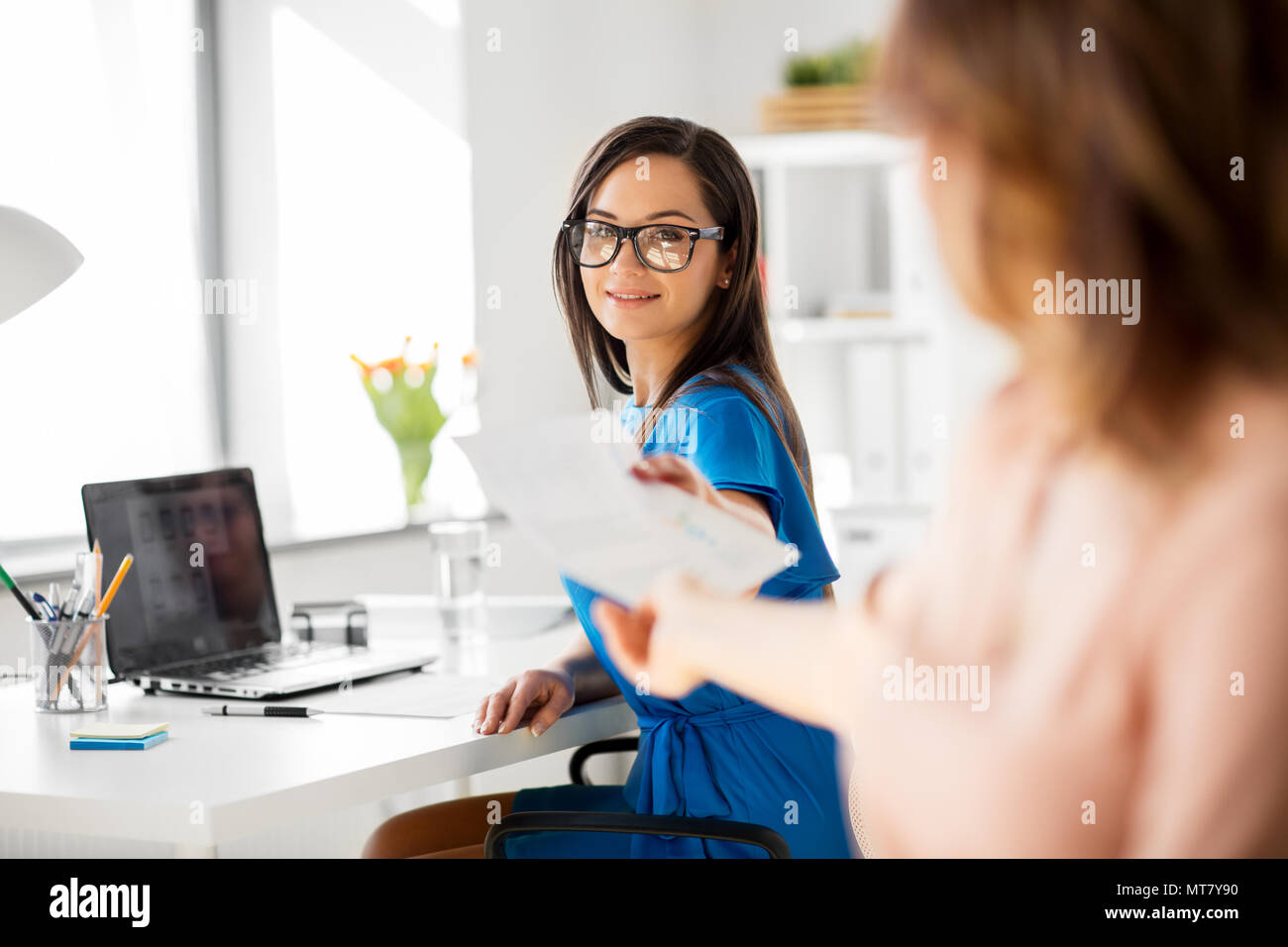 Businesswomen giving other papers hi-res stock photography and images ...