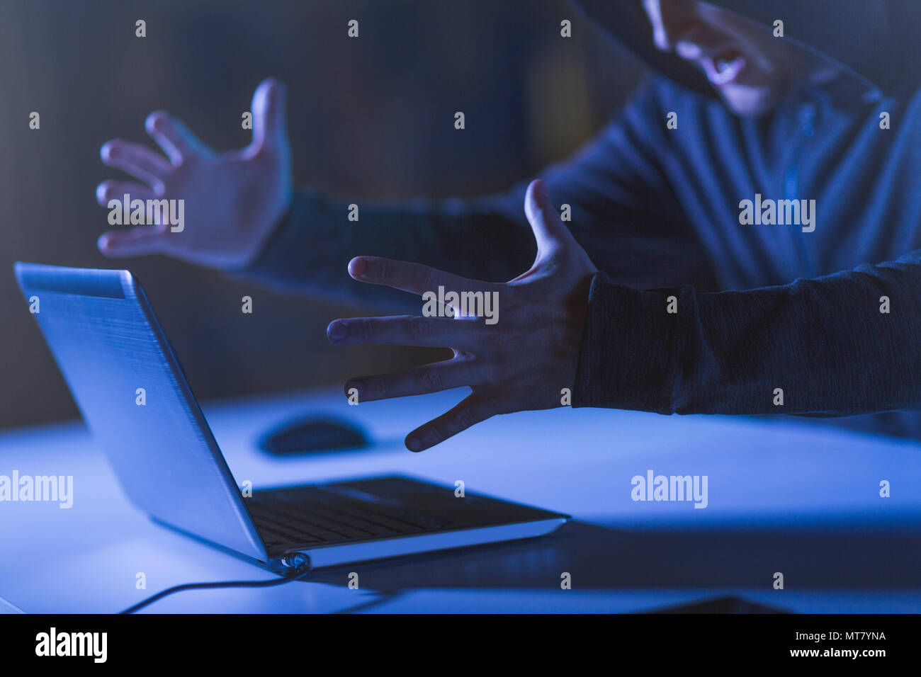 angry hacker with laptop shouting in dark room Stock Photo - Alamy