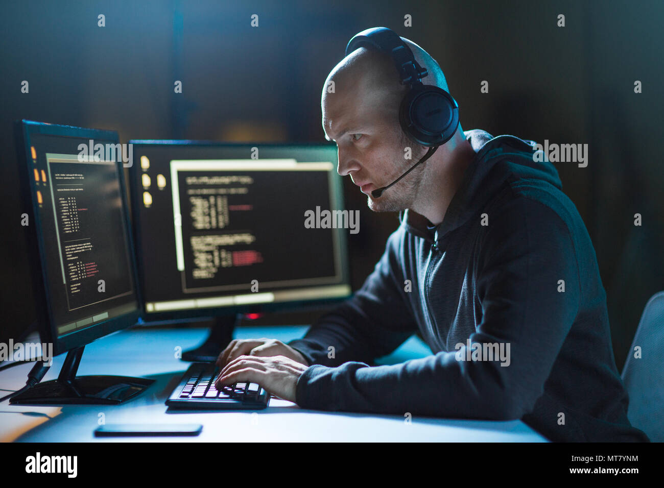 hacker with computer and headset in dark room Stock Photo - Alamy