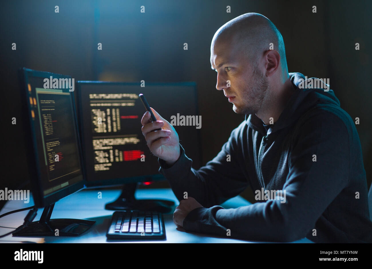 hacker with smartphone and computers in dark room Stock Photo - Alamy