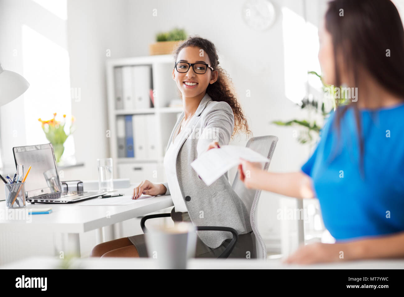 businesswomen giving each other papers at office Stock Photo - Alamy