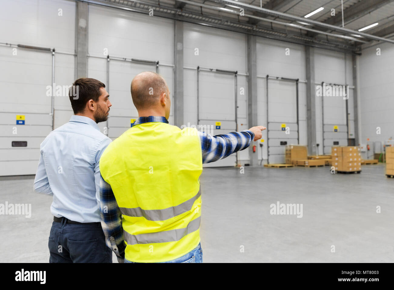 businessman showing warehouse to worker Stock Photo - Alamy