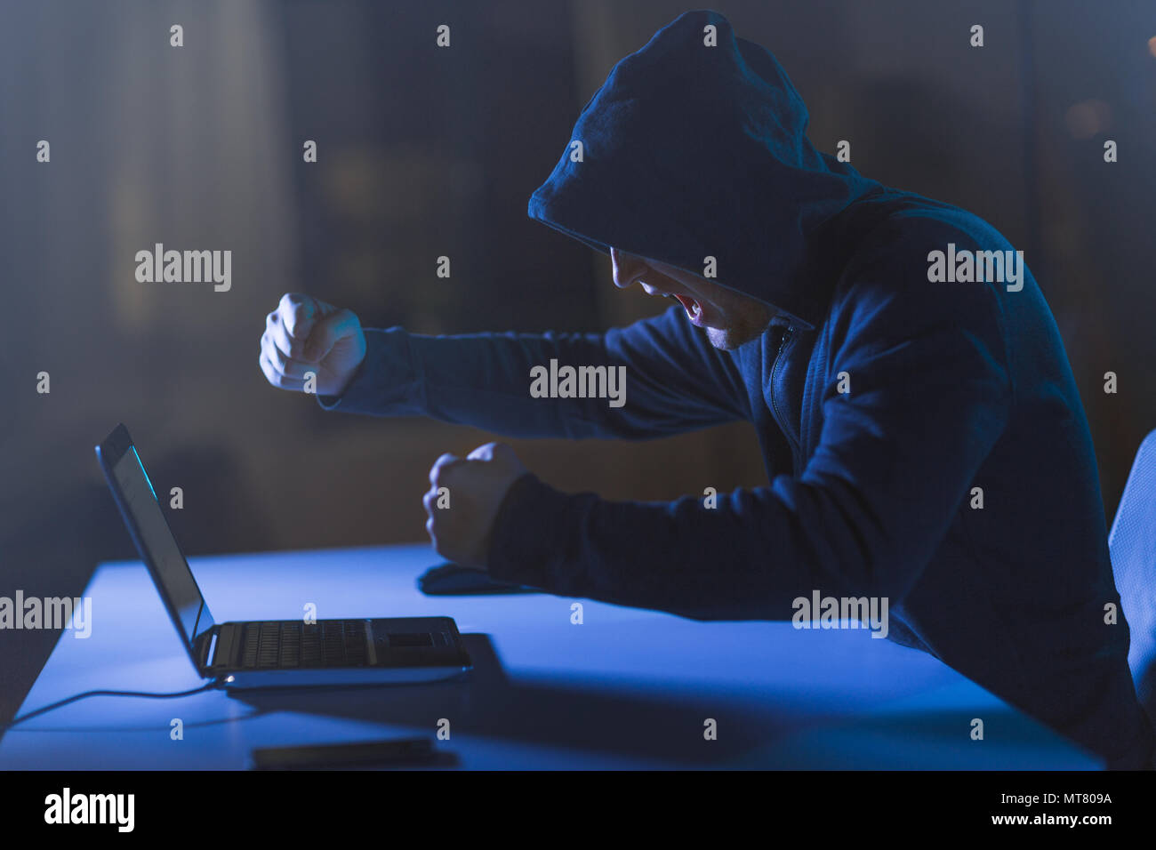 angry hacker with laptop shouting in dark room Stock Photo - Alamy