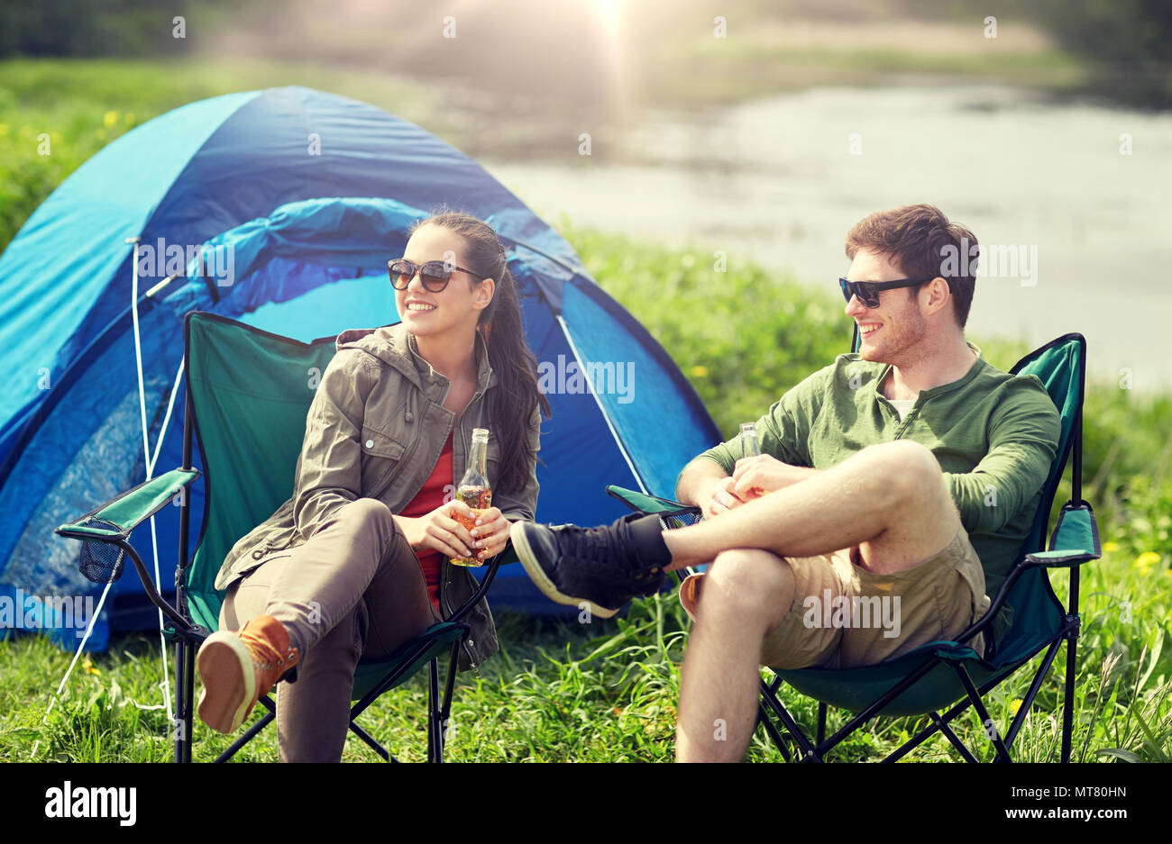 happy couple drinking beer at campsite tent Stock Photo - Alamy