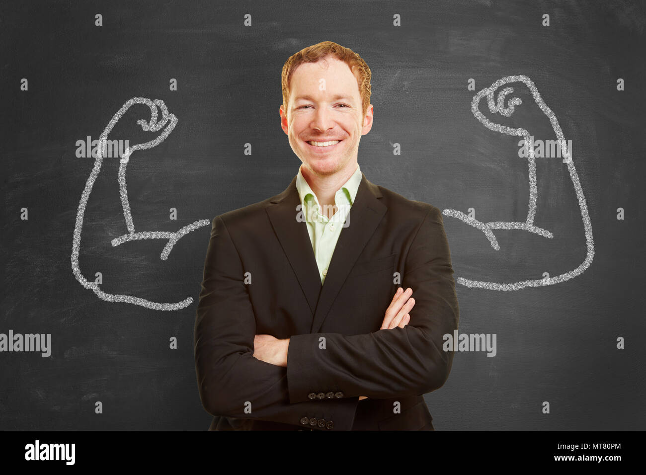 Motivated businessman with painted muscles in front of a blackboard ...