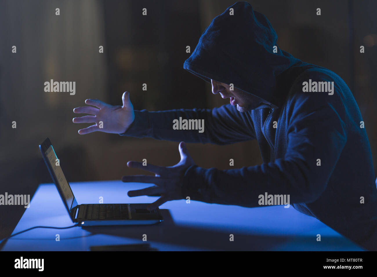 angry hacker with laptop computer in dark room Stock Photo - Alamy