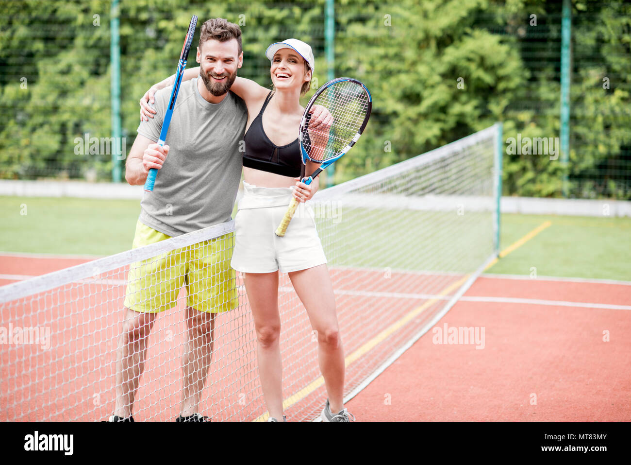 Young couple having fun standing on the tennis court Stock Photo - Alamy