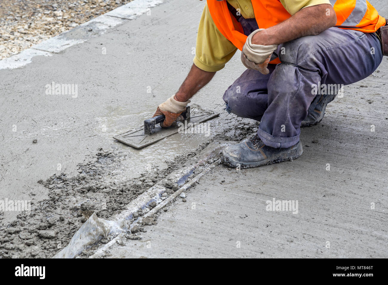 Worker leveling concrete with trowel, hands spreading poured concrete ...