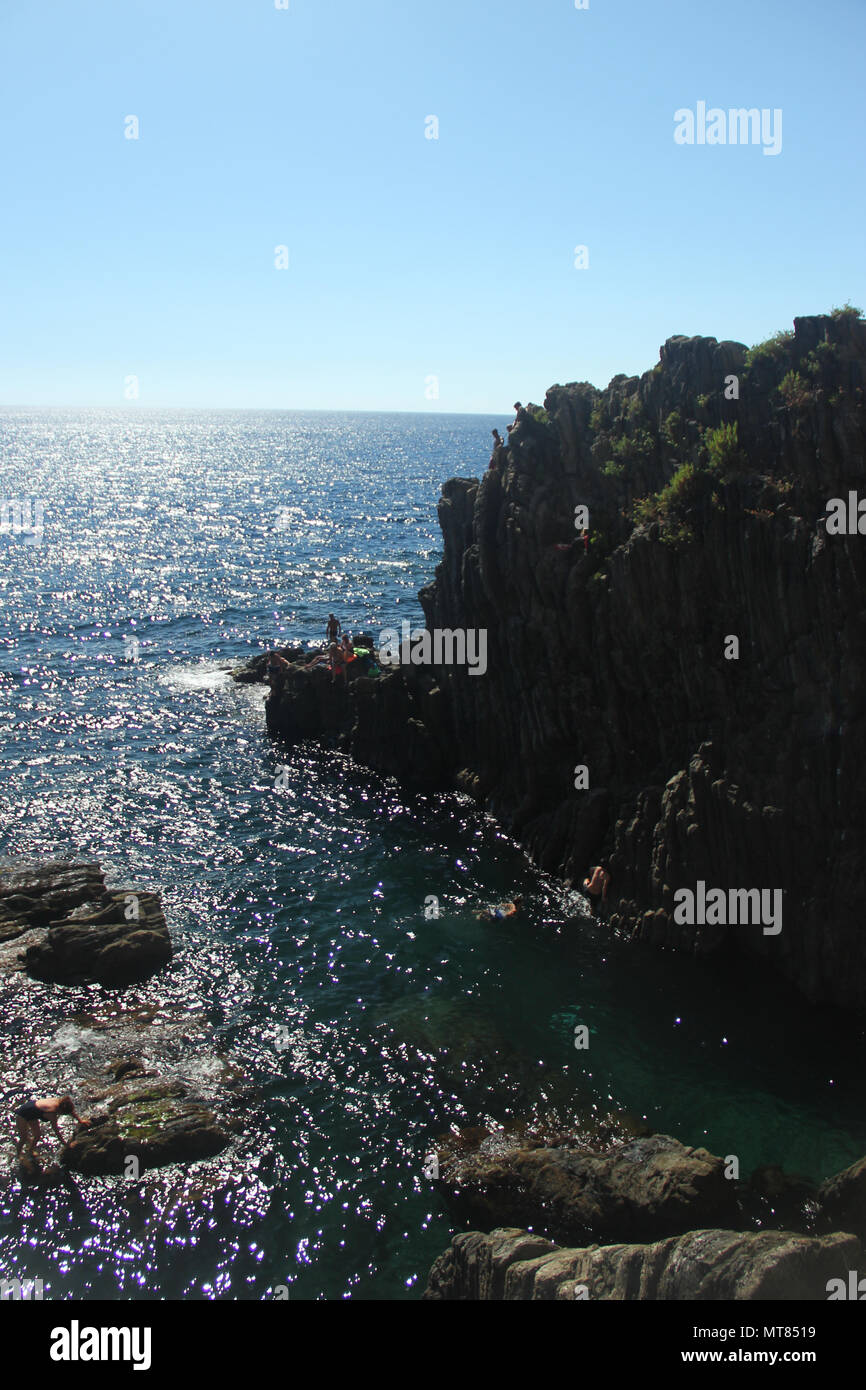 Diving from the rocks into the beautiful blue sea of Riomaggiore, Italy ...