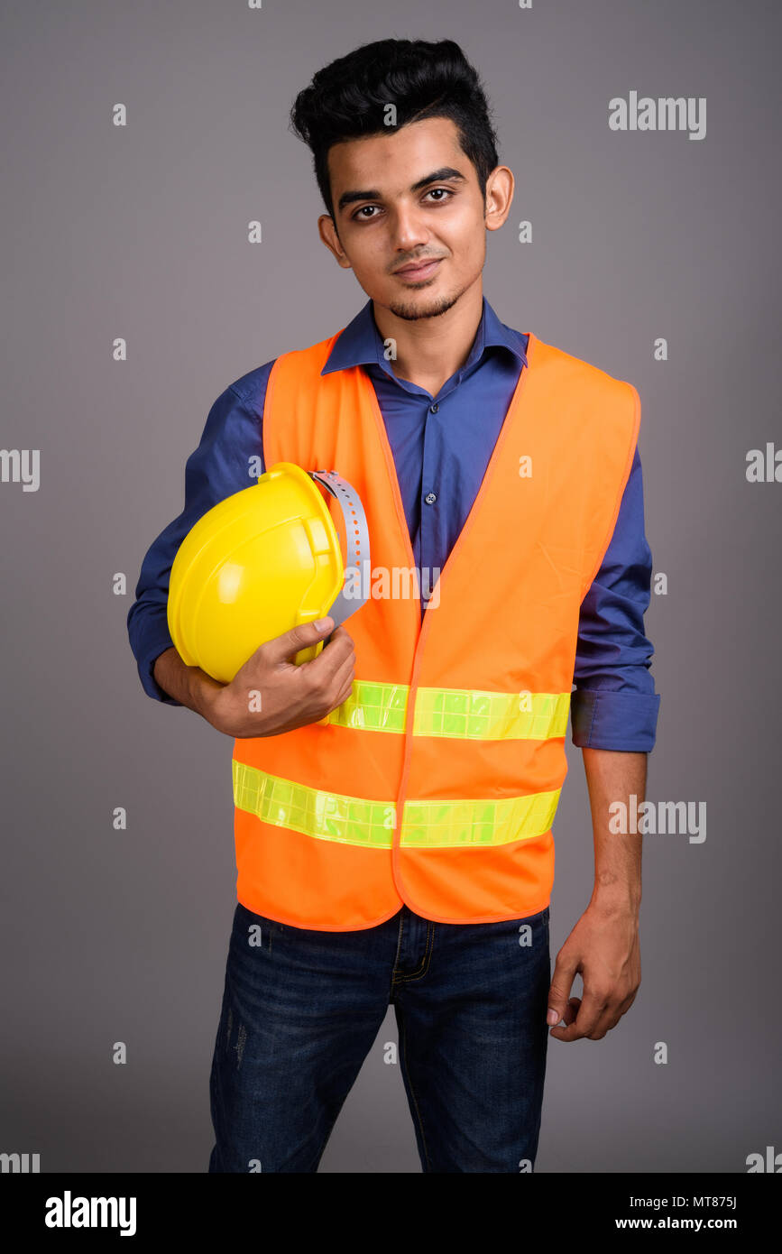 Young Indian man construction worker against gray background Stock ...