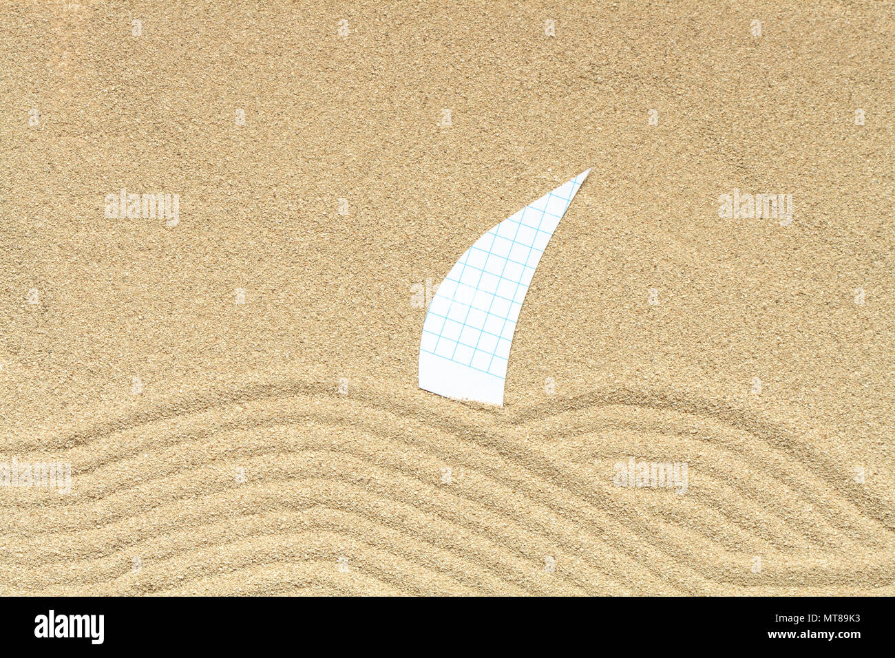 Paper sail lying on sand background with drawing waves Stock Photo - Alamy