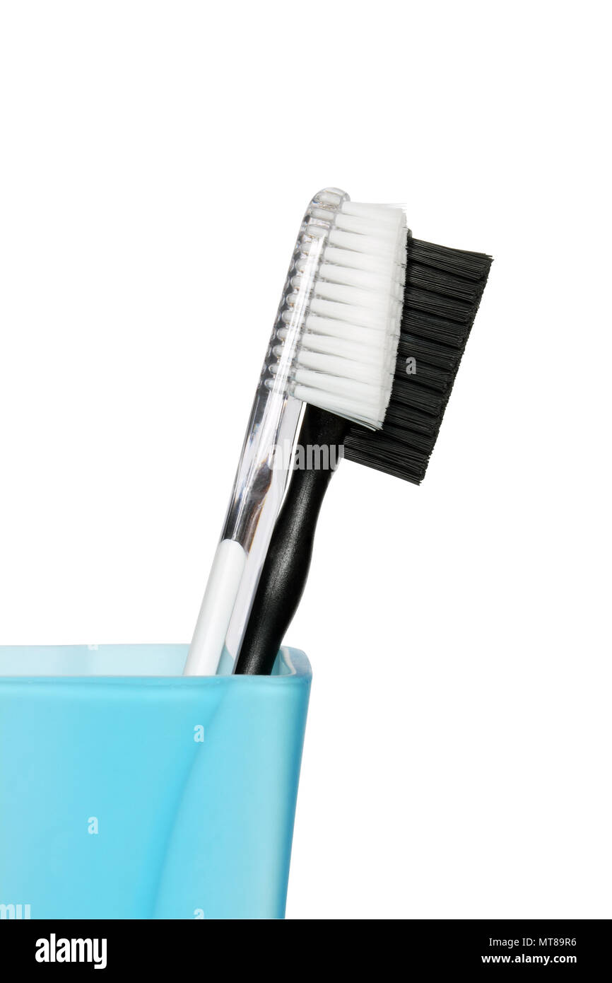Black and white toothbrushes in blue glass. Isolated with clipping path ...