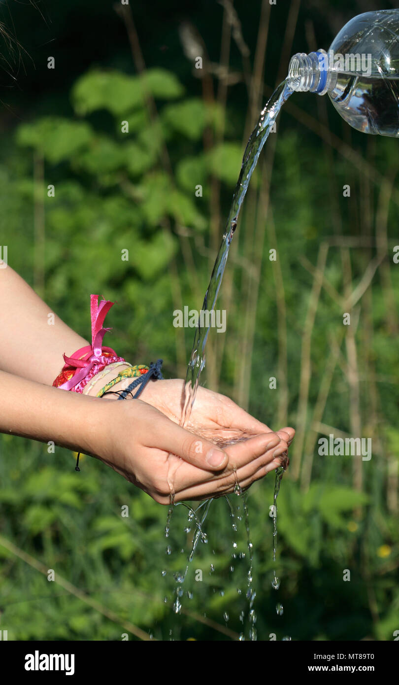 Water pouring into womans hands from plastic bottle on nature ...
