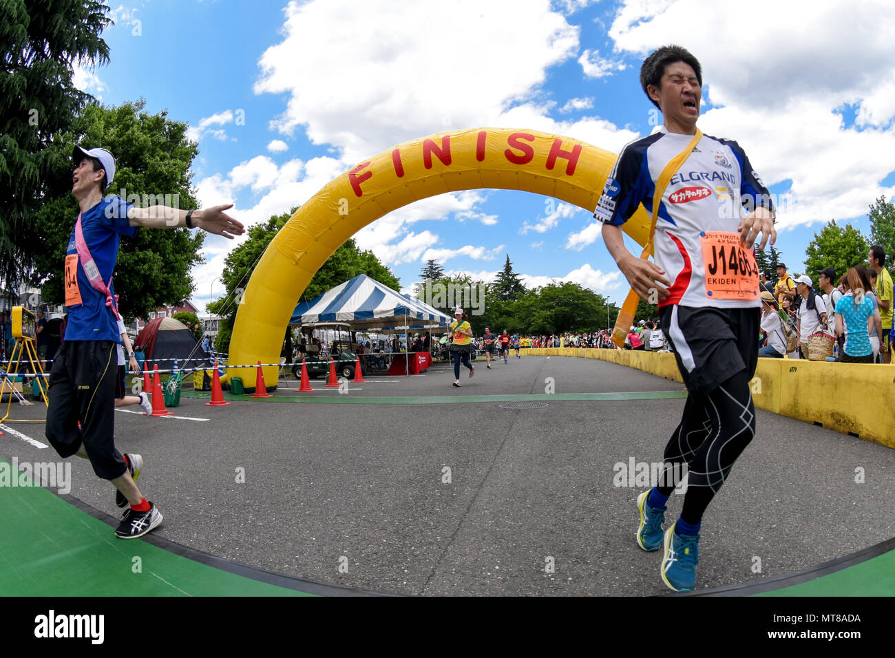 Participants in the Ekiden Race cross the finish line at Yokota Air ...