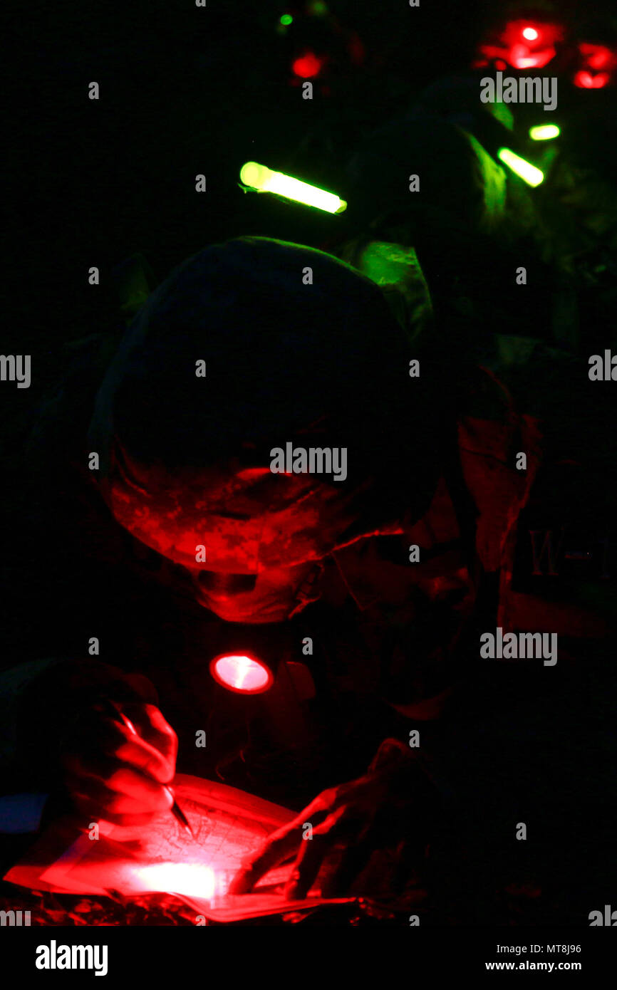 A competitor plots points on a map at the night land navigation event ...