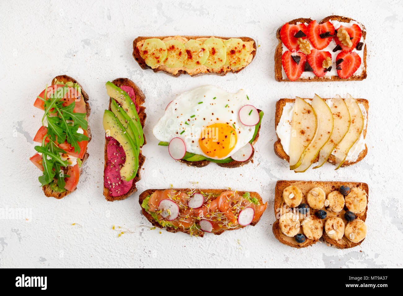 Assortment of healthy breakfast toasts on a white rustic background ...