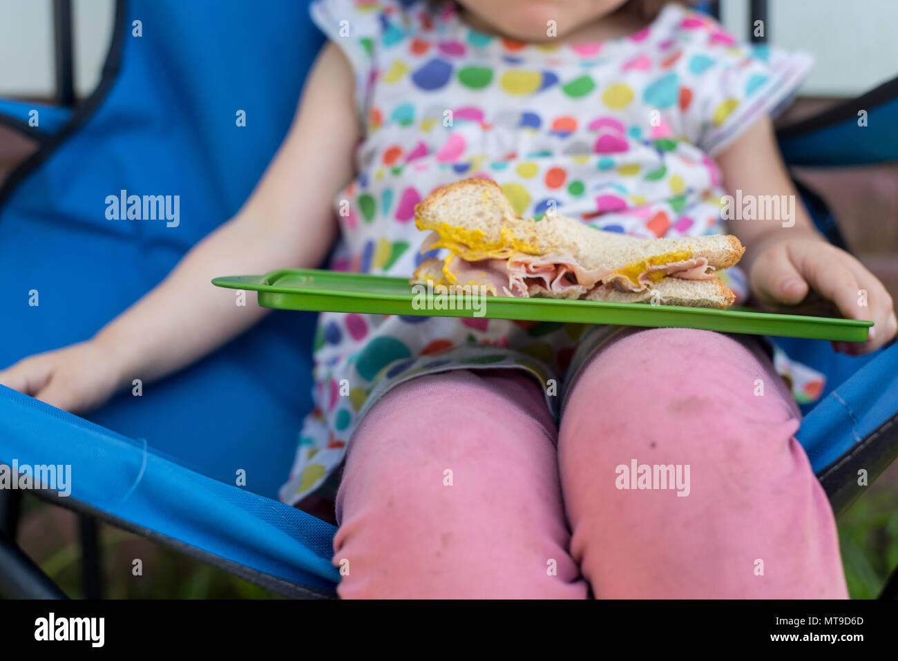 A toddler girl holding a ham sandwich outside Stock Photo - Alamy