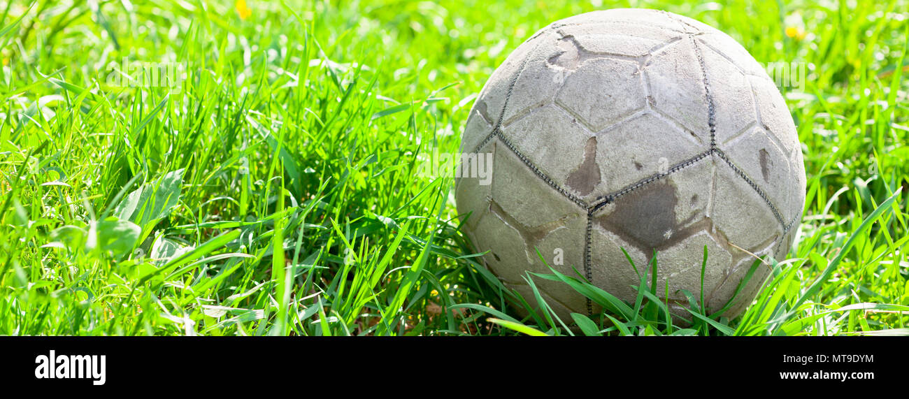 Old soccer ball forgotten in the green grass field. The football ...