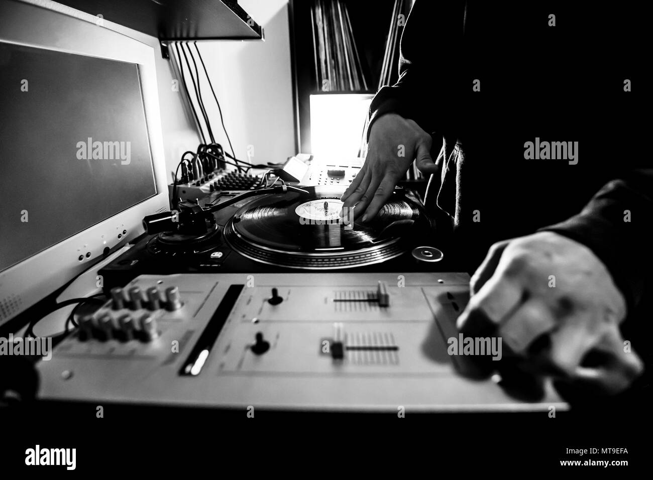Dj in studio uses turntable and mixer for scratching. Black and white ...