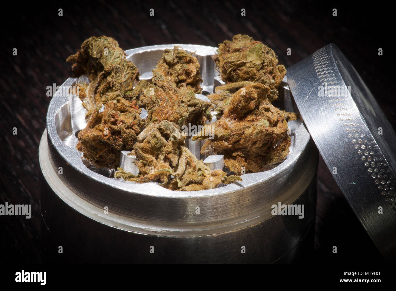 Metal grinder with marijuana isolated on a black wooden table Stock ...