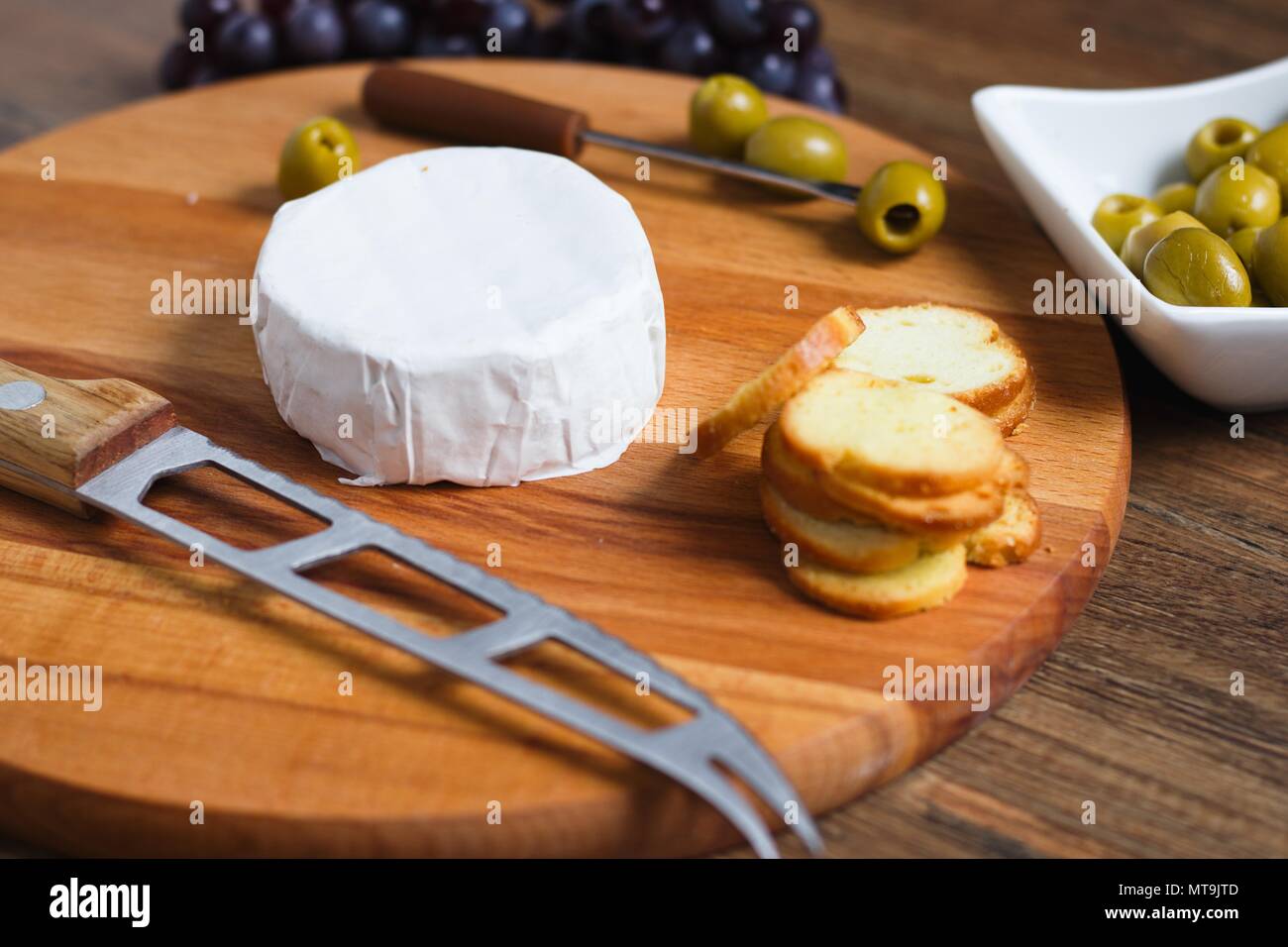 Soft cheese with white rind (camembert or brie) on wooden board with ...